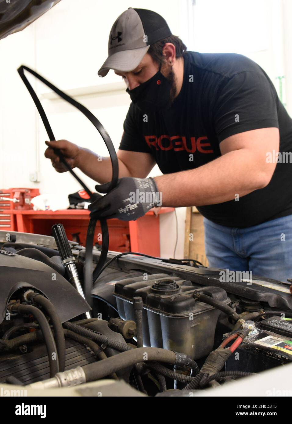 Mark Riedel prepares to install a serpentine belt after replacing the ...