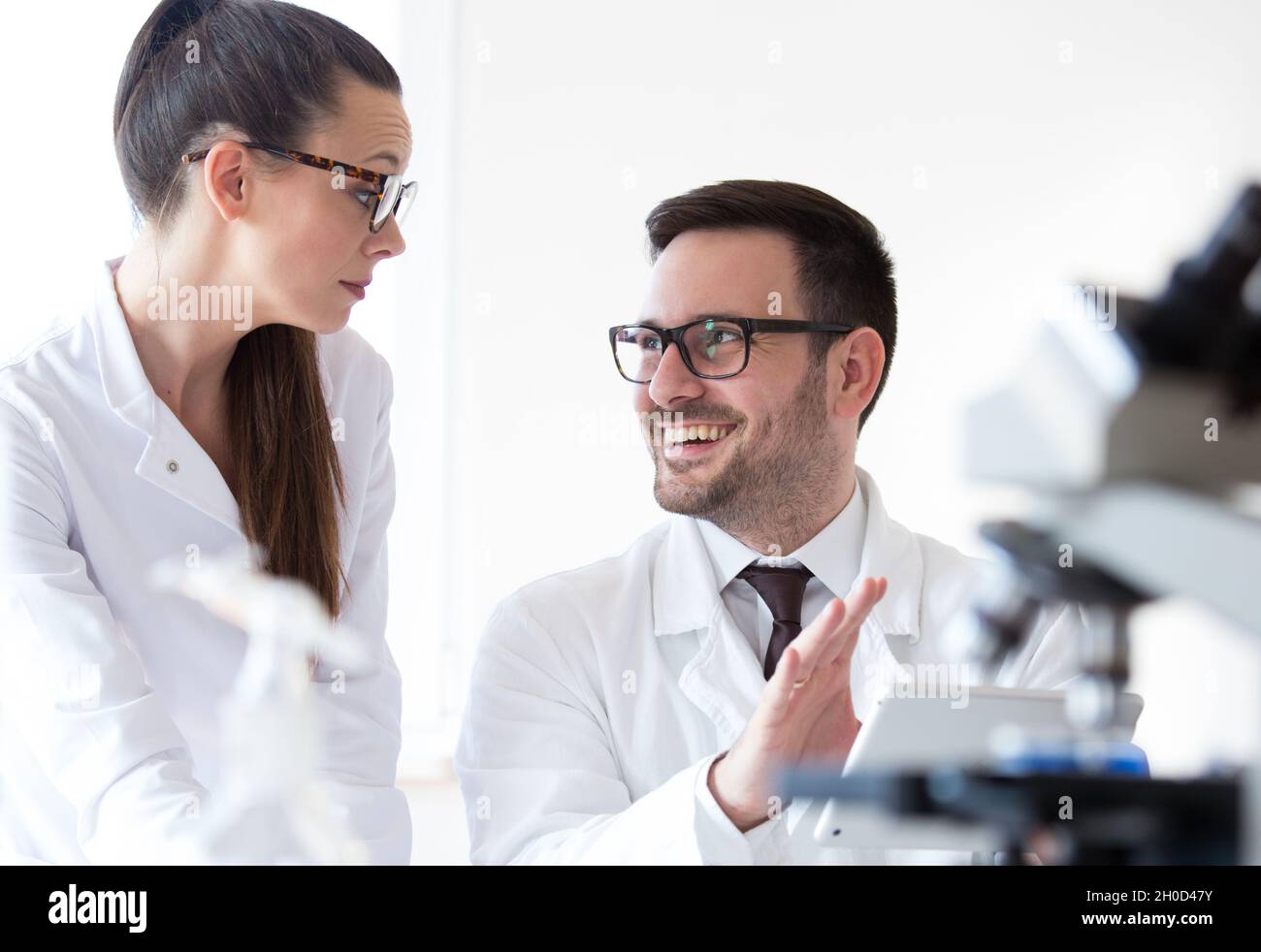 Man and woman scientists analyzing data from microscope test Stock ...