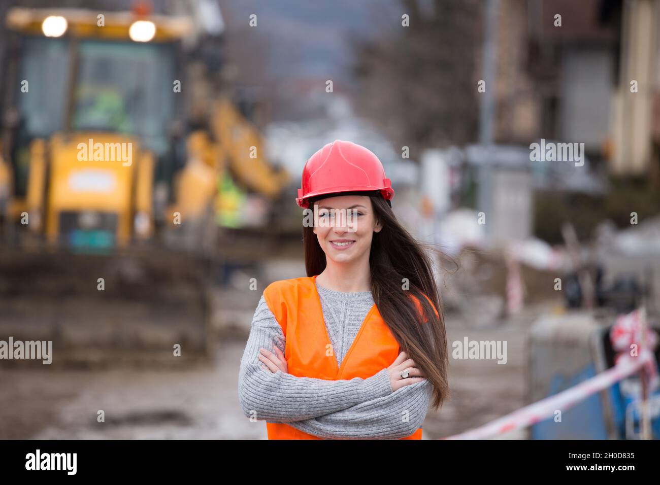 Pretty young woman engineer standing in front of excavator at ...