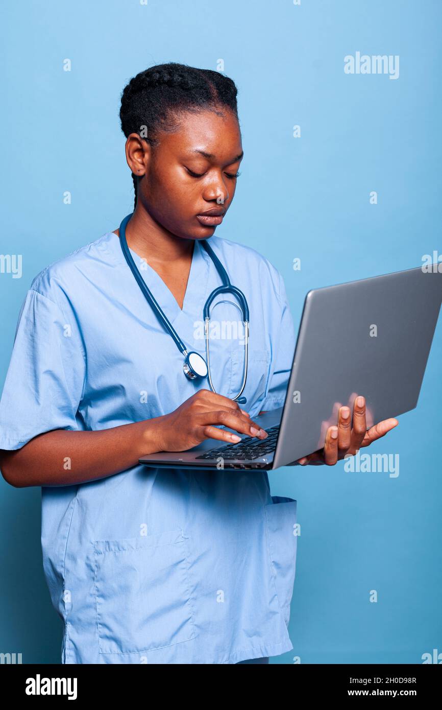 African american practitioner nurse holding laptop computer typing ...