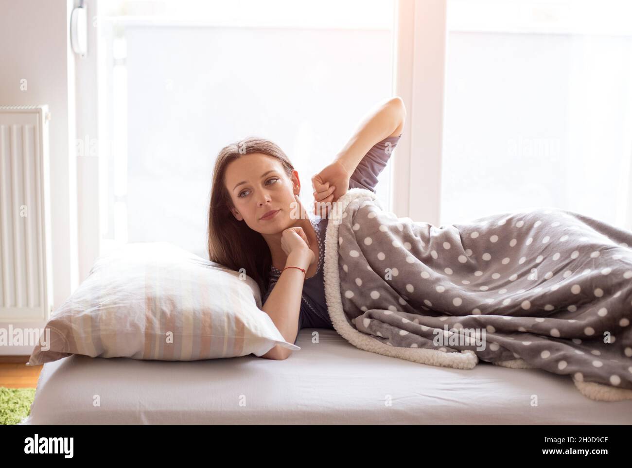 Pretty young woman waking up and stretching in bed beside window Stock ...