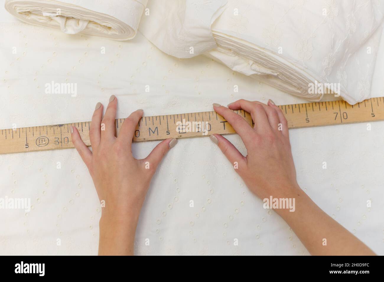 Female hands using wooden tailor ruler to measure cotton fabric ...