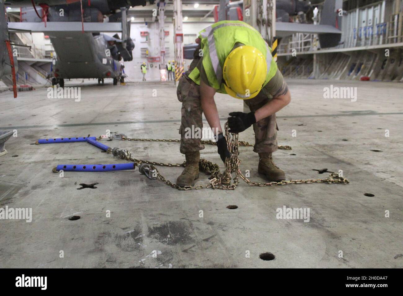 An Air Force mechanic prepares tie down chains for use in securing an ...