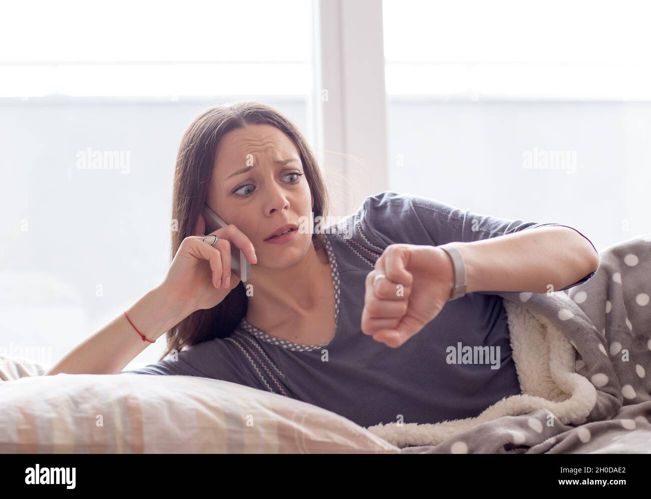 Pretty girl lying in bed in morning and getting phone call because she ...