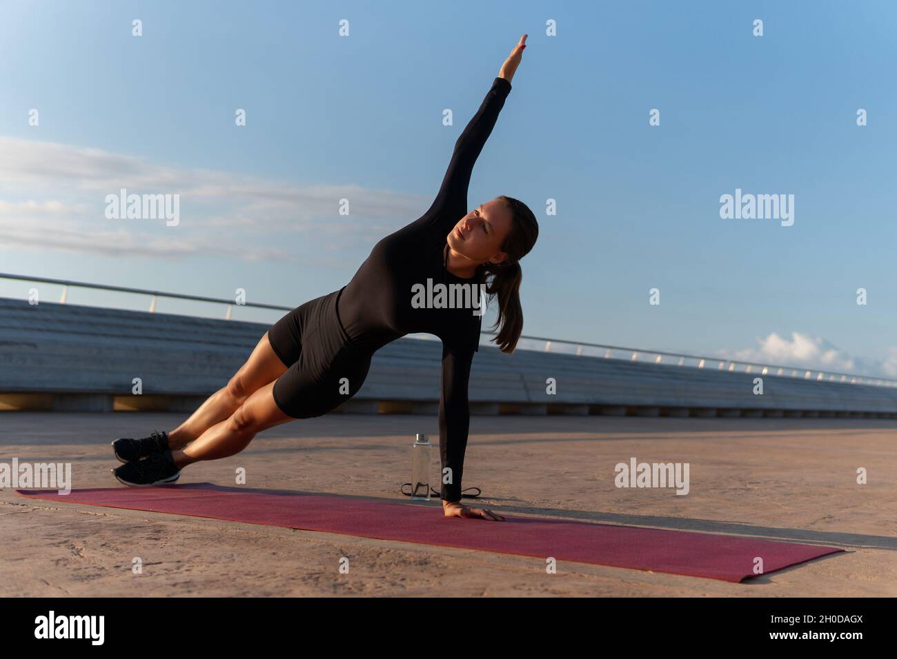 Female athlete doing side plank exercise with raised arm on mat during ...
