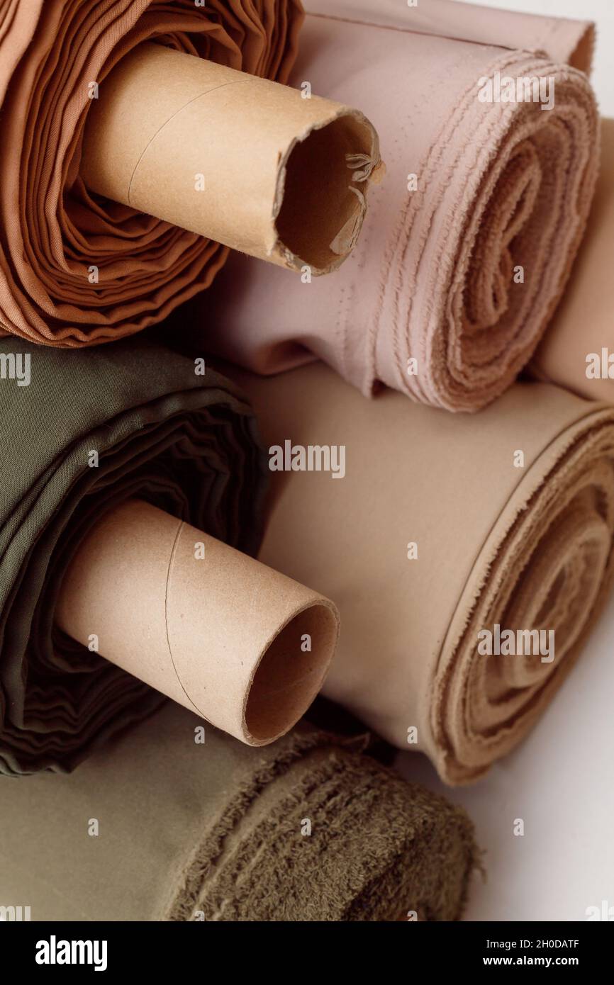 Stack of pastel color fabric rolls of synthetic and natural fabrics ...