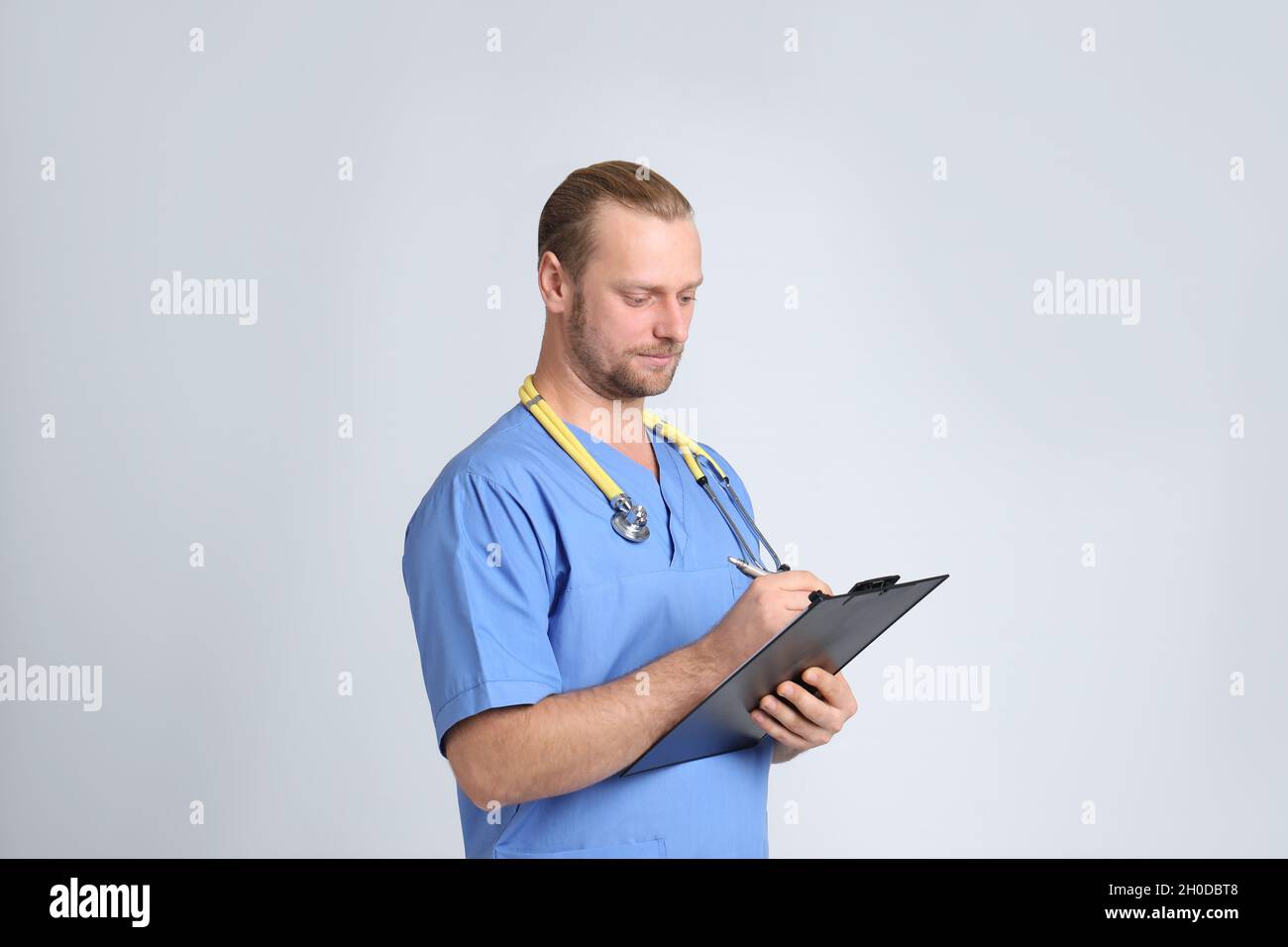 Portrait of medical assistant with stethoscope and clipboard on color ...