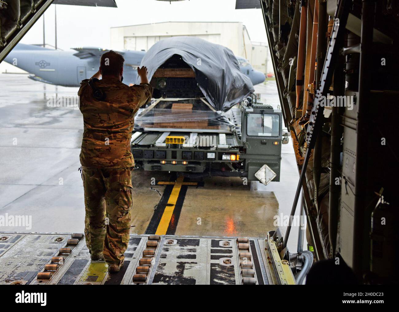 U.S. Air Force personnel load heavy drop pallets onto a C-130 aircraft ...