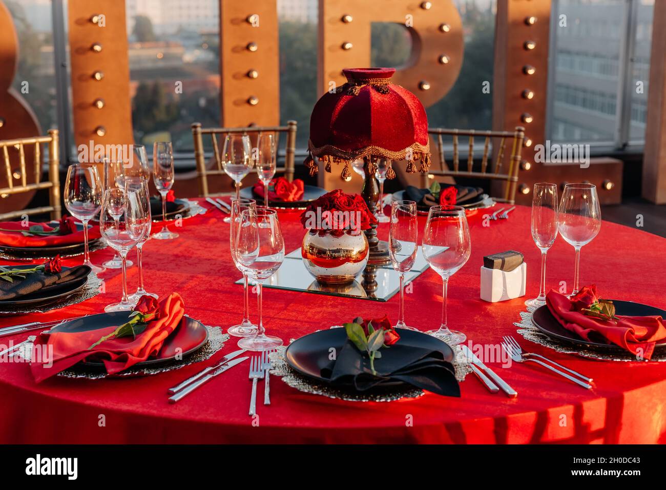 Guests table setting for banquet in black, red and gold style. Elegant dinner: decor, tablecloth ...