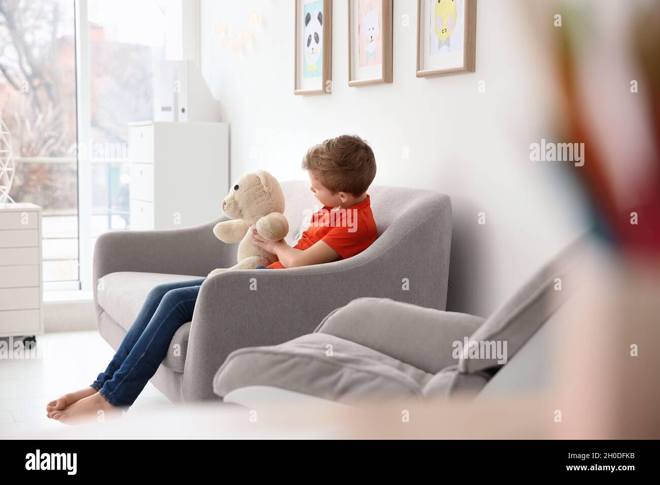 Little autistic boy sitting on sofa with toy at home Stock Photo - Alamy