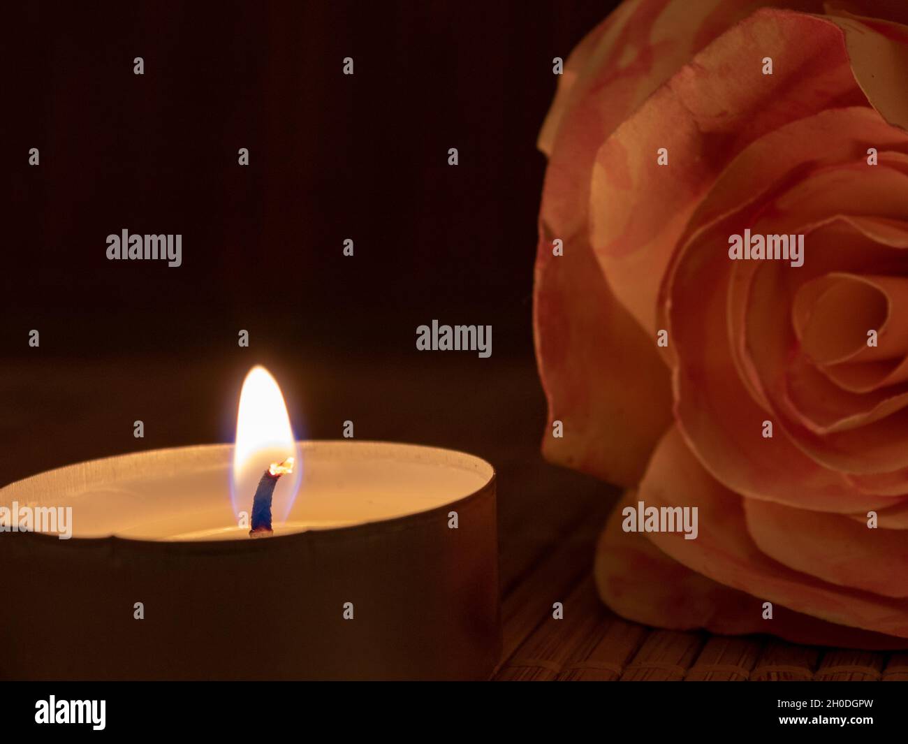 Romantic candlelight with a soft glowing flame and a delicate pink rose ...