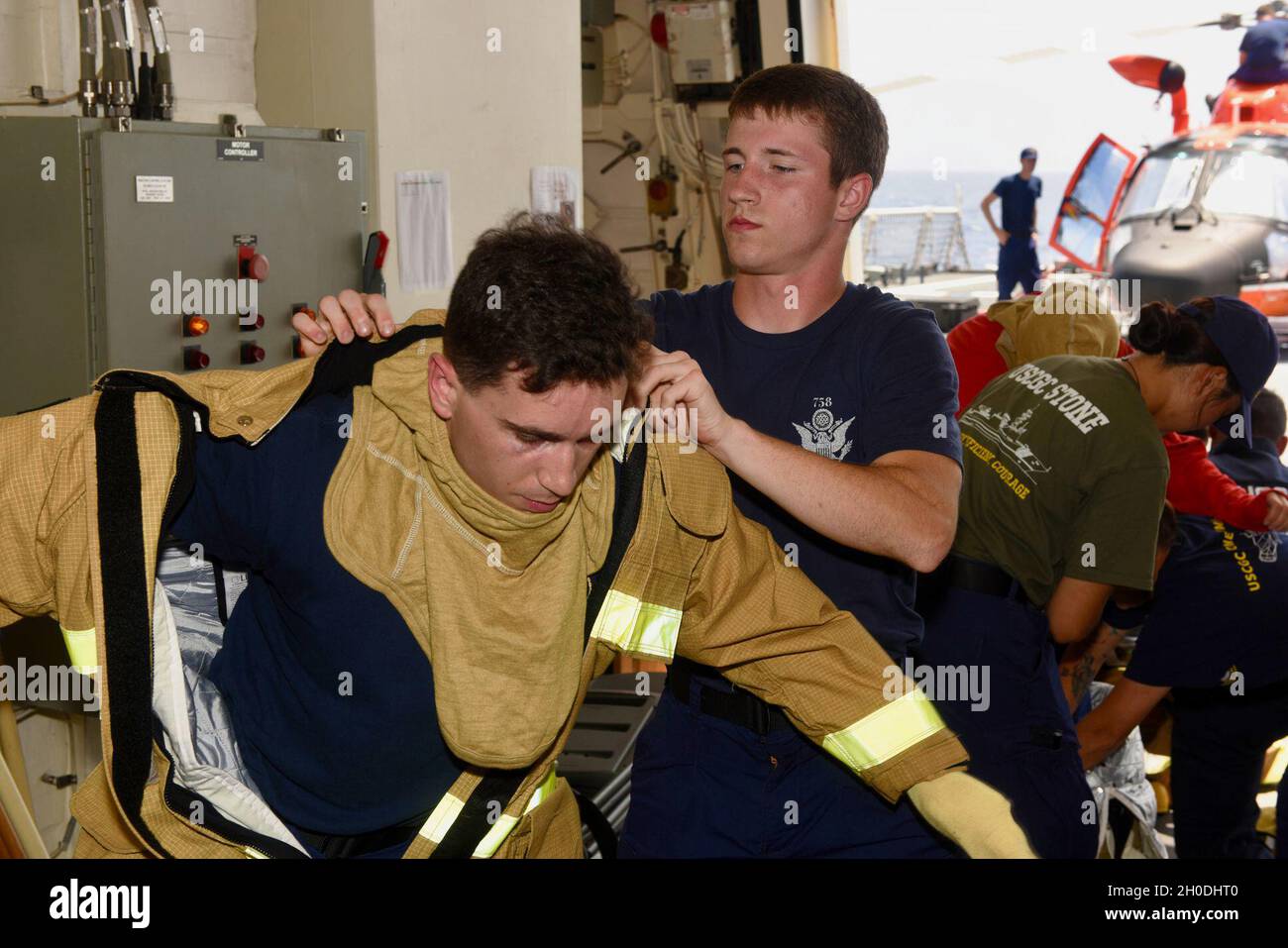 Fireman Lance Holland assists Petty Officer 3rd Class Morgan Swaim in ...