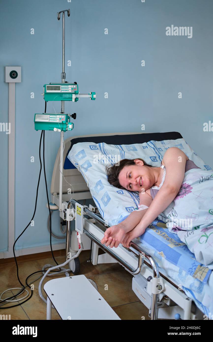 Smiling woman on clinic bed with anesthesia during labor pains. A ...