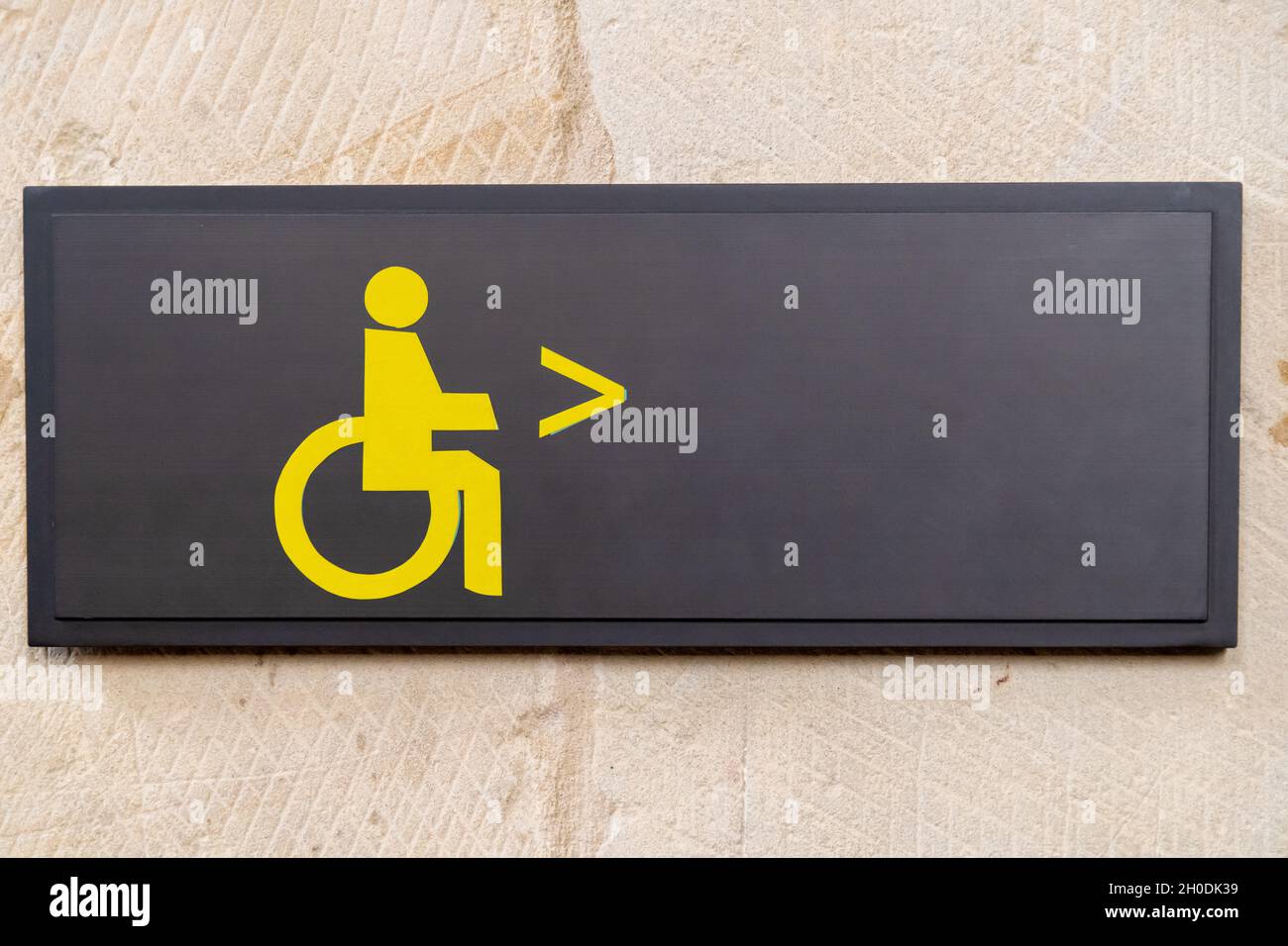 Yellow wheelchair sign on dark background with an arrow to the right ...
