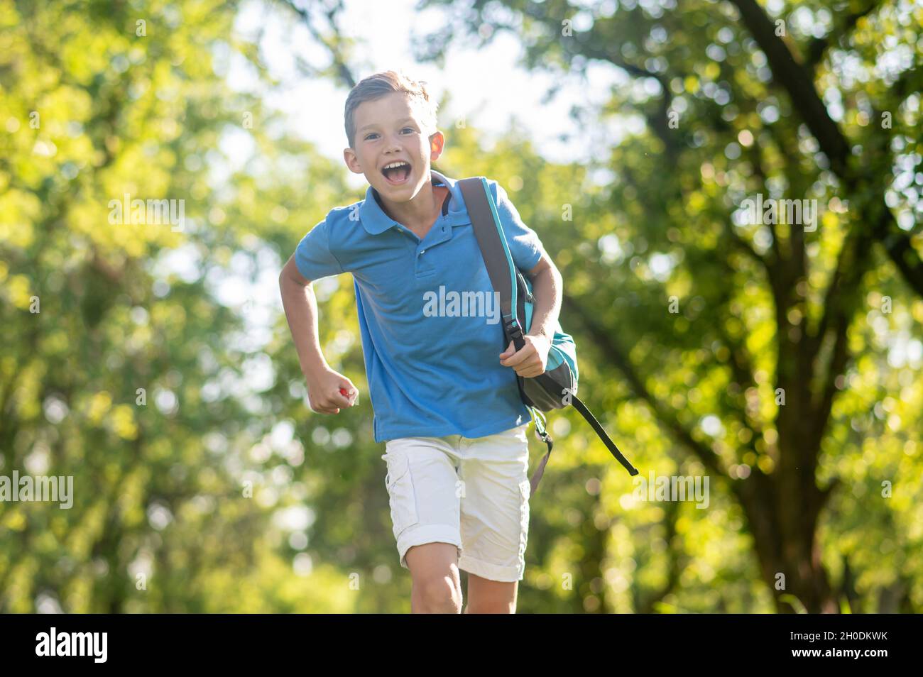 Enthusiastic boy with school bag running in park Stock Photo - Alamy