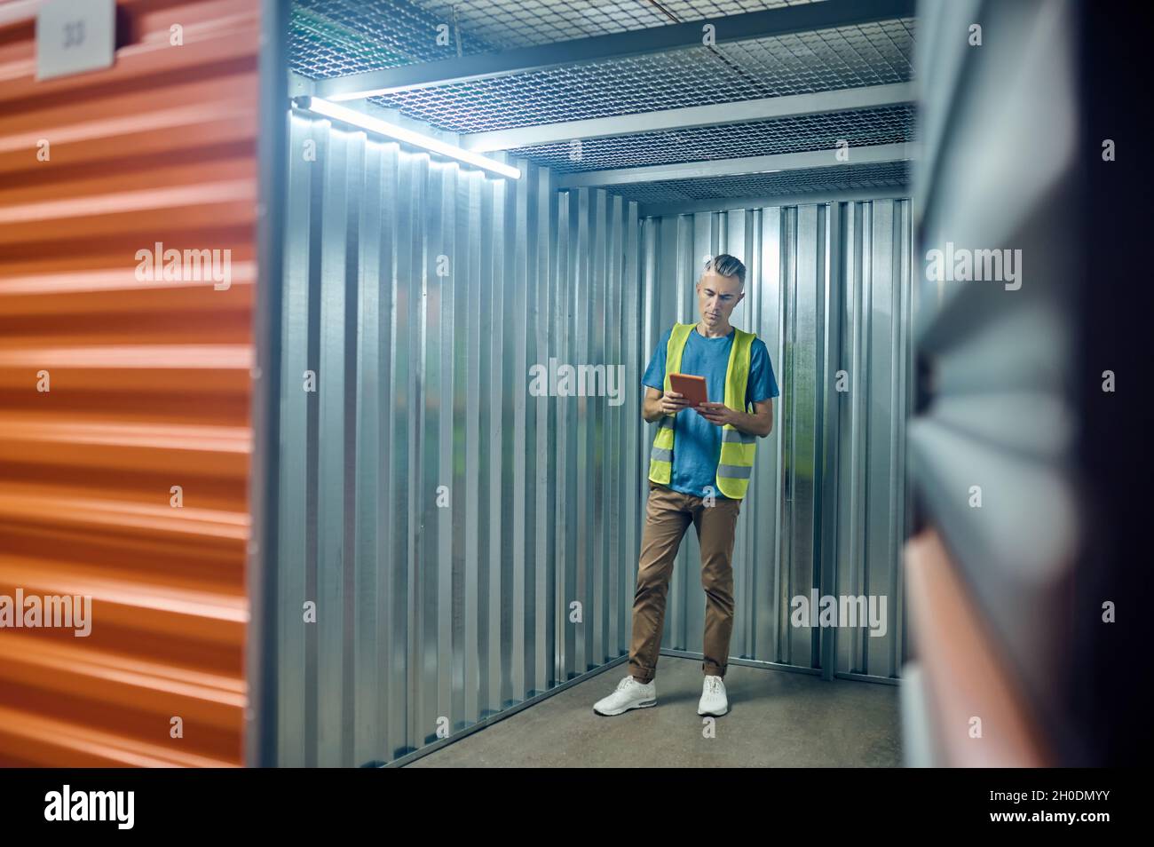Man looking intently at work tablet in garage Stock Photo - Alamy