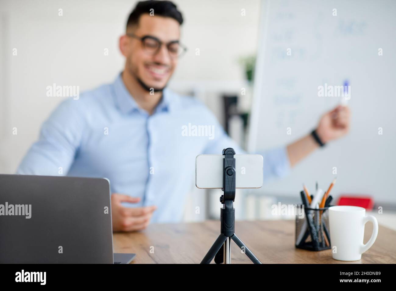 Cheerful Arab male teacher giving online English lesson, using ...