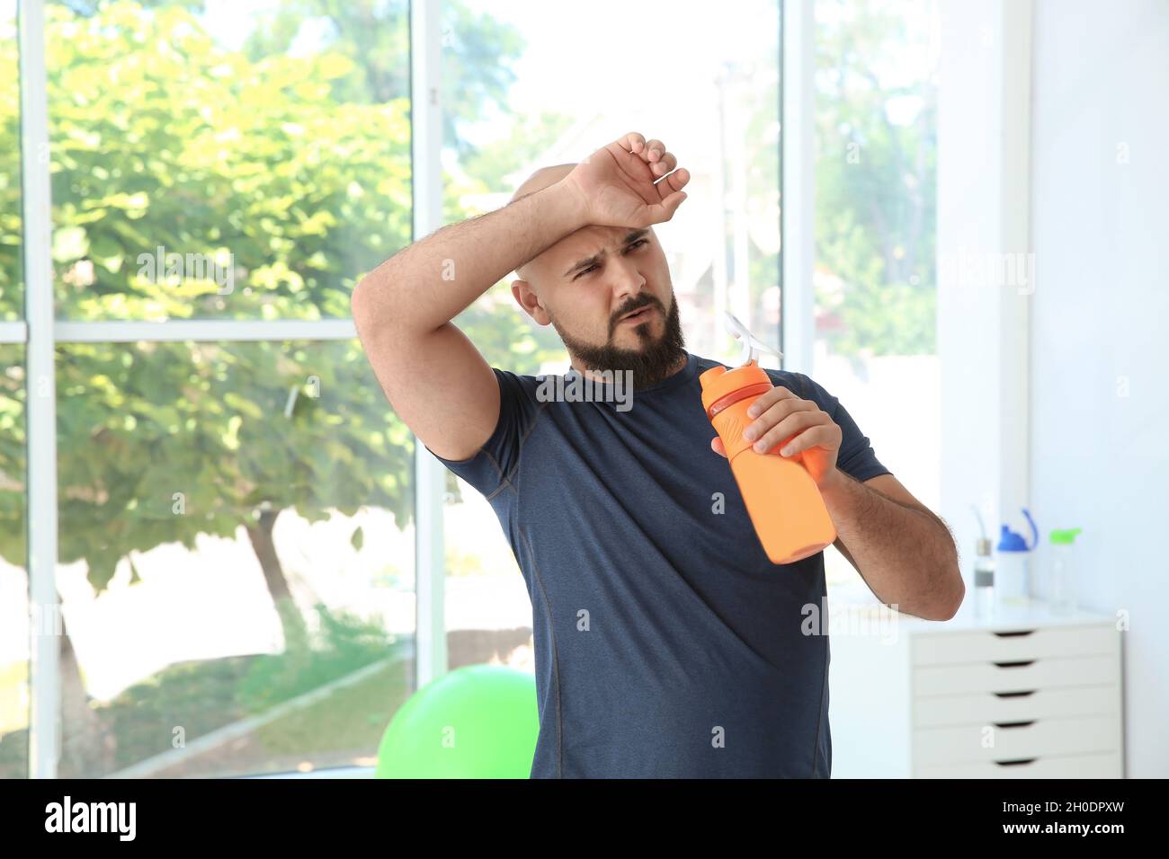 Tired overweight man with bottle of water in gym Stock Photo - Alamy