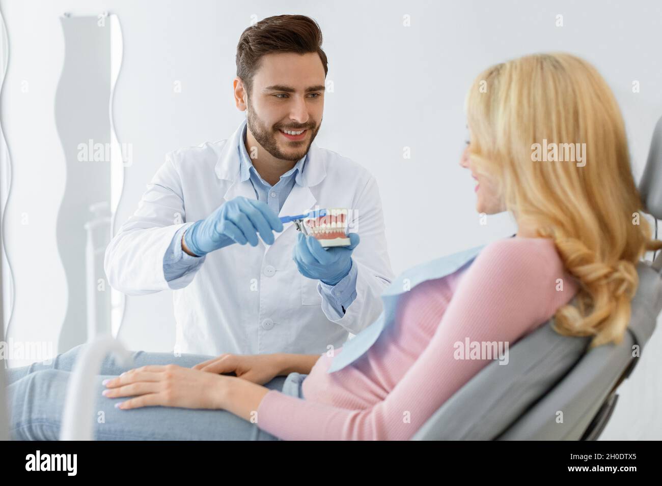 Dentist holding jaw and tooth brush, having conversation with patient ...