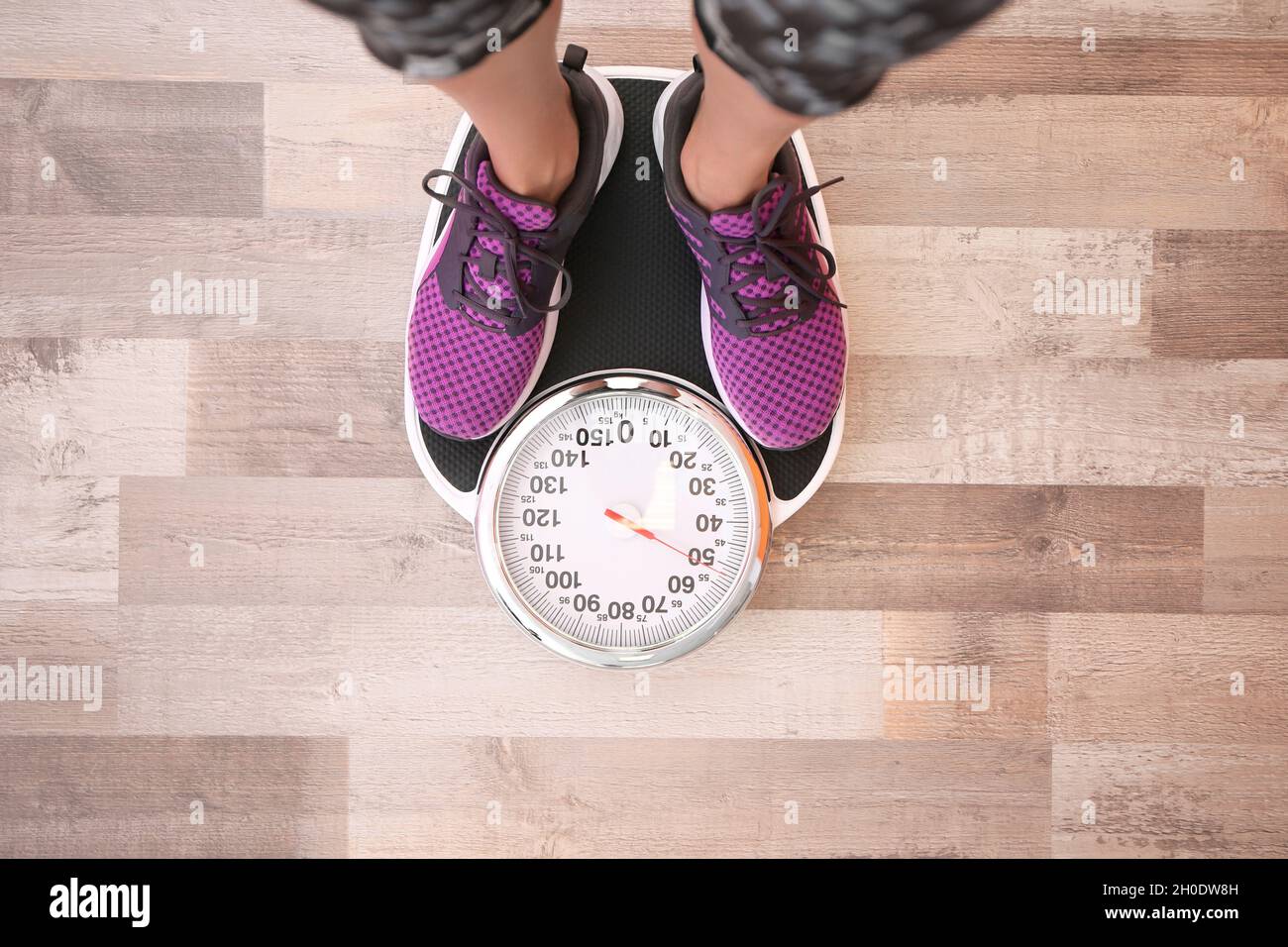 Woman measuring her weight using scales on floor, top view Stock Photo ...
