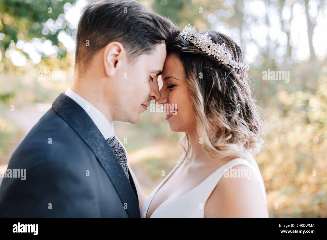 Portrait of a just married couple bringing their foreheads together in ...