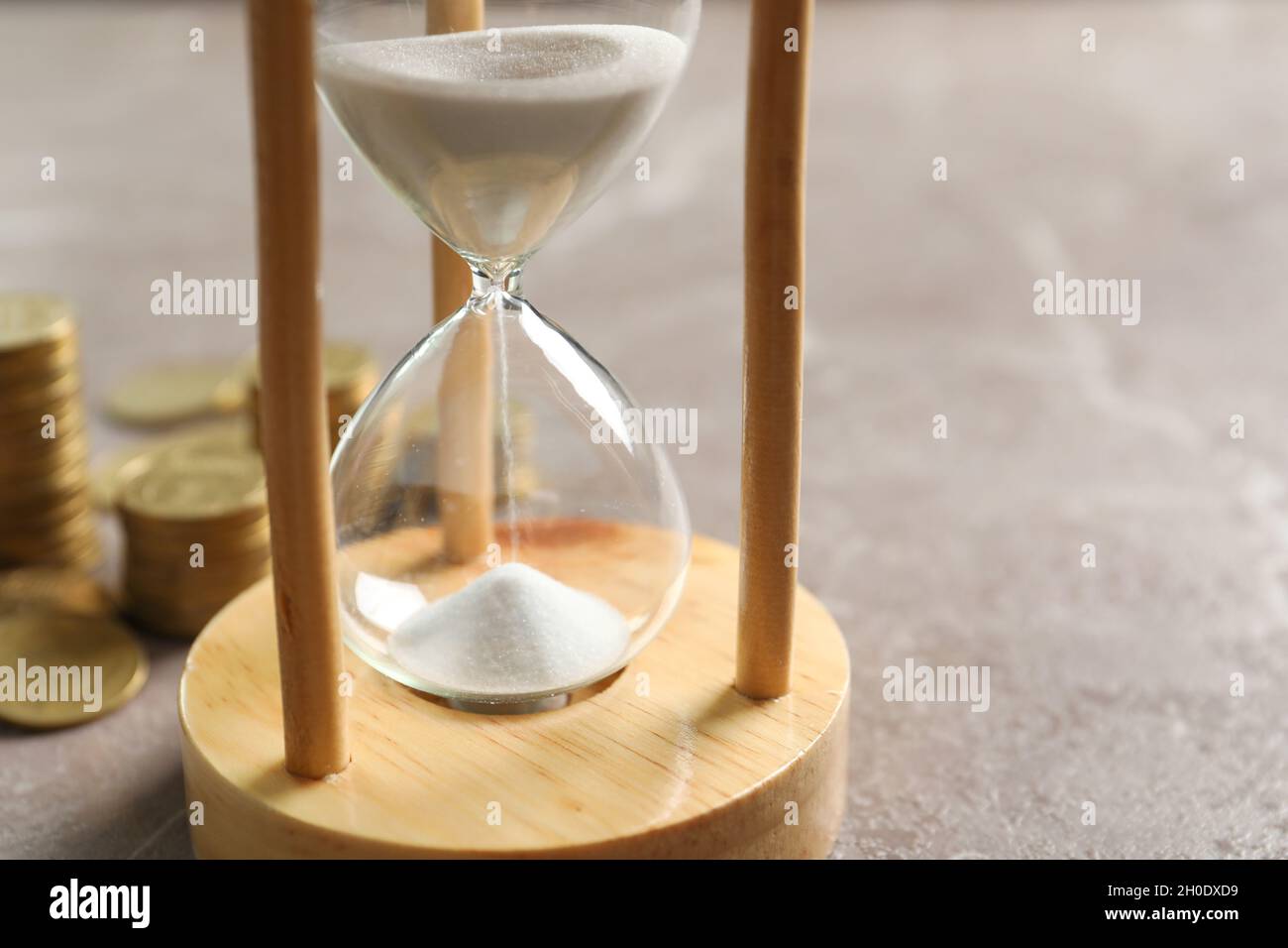 Hourglass with flowing sand and coins on table. Time management Stock ...