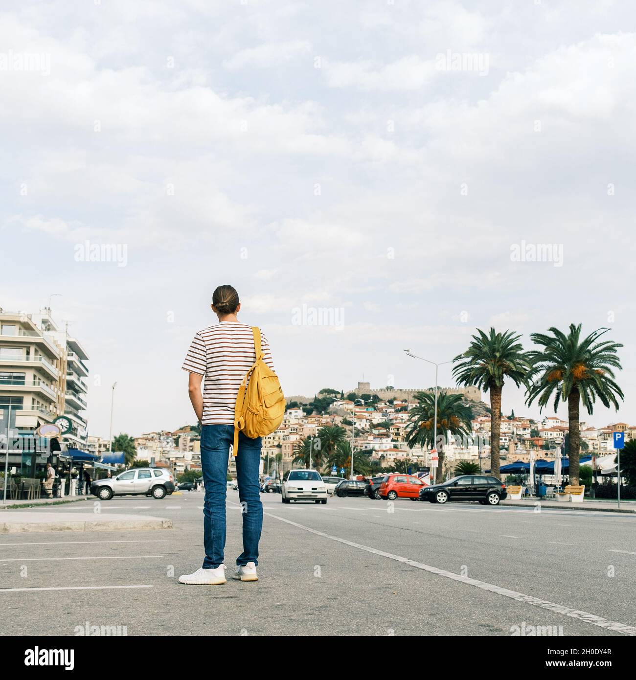 Young man with backpack walking on the street of city Kavala, Greece ...