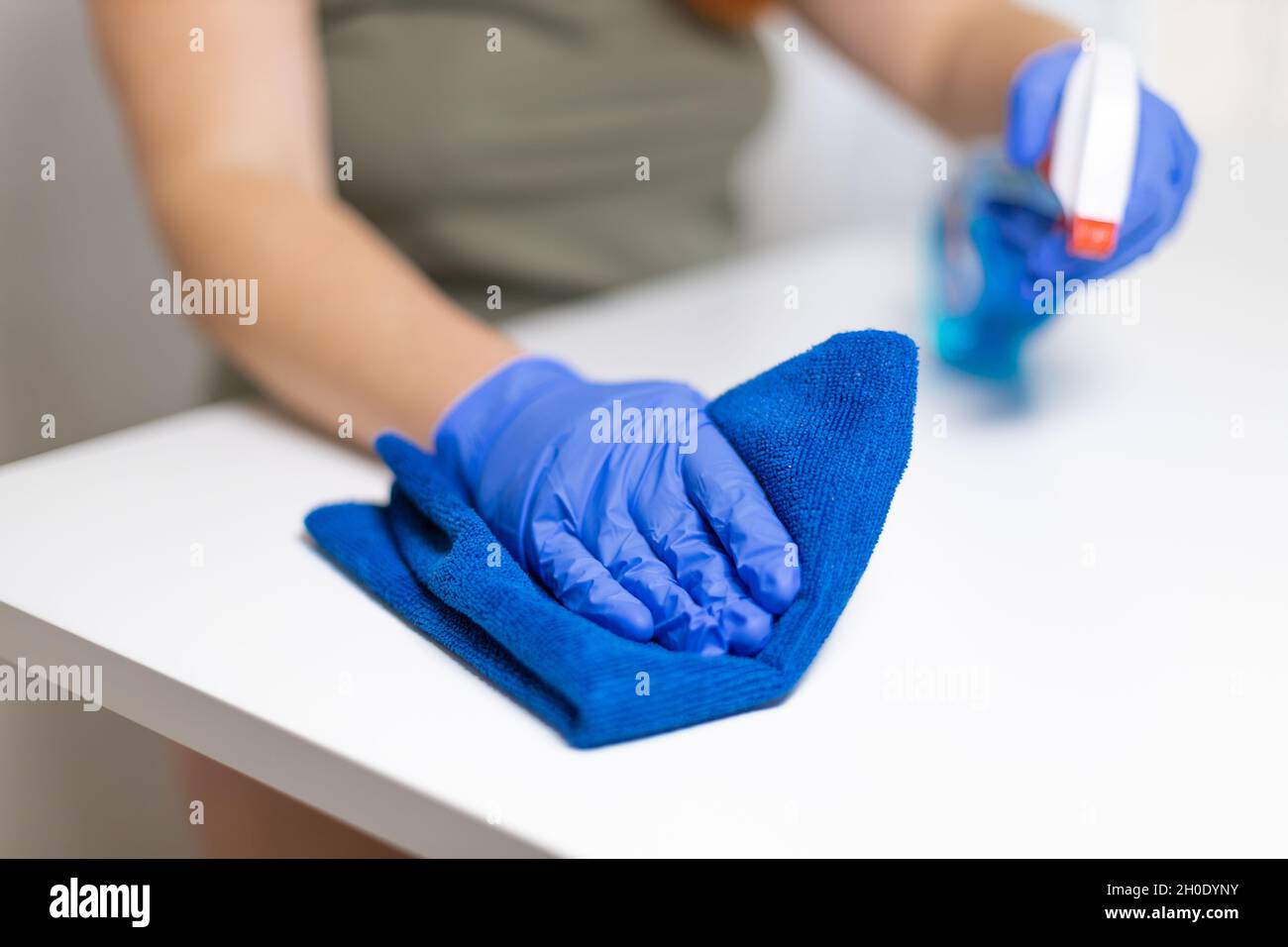 Young woman housekeeper is cleaning, wiping down table surface with ...
