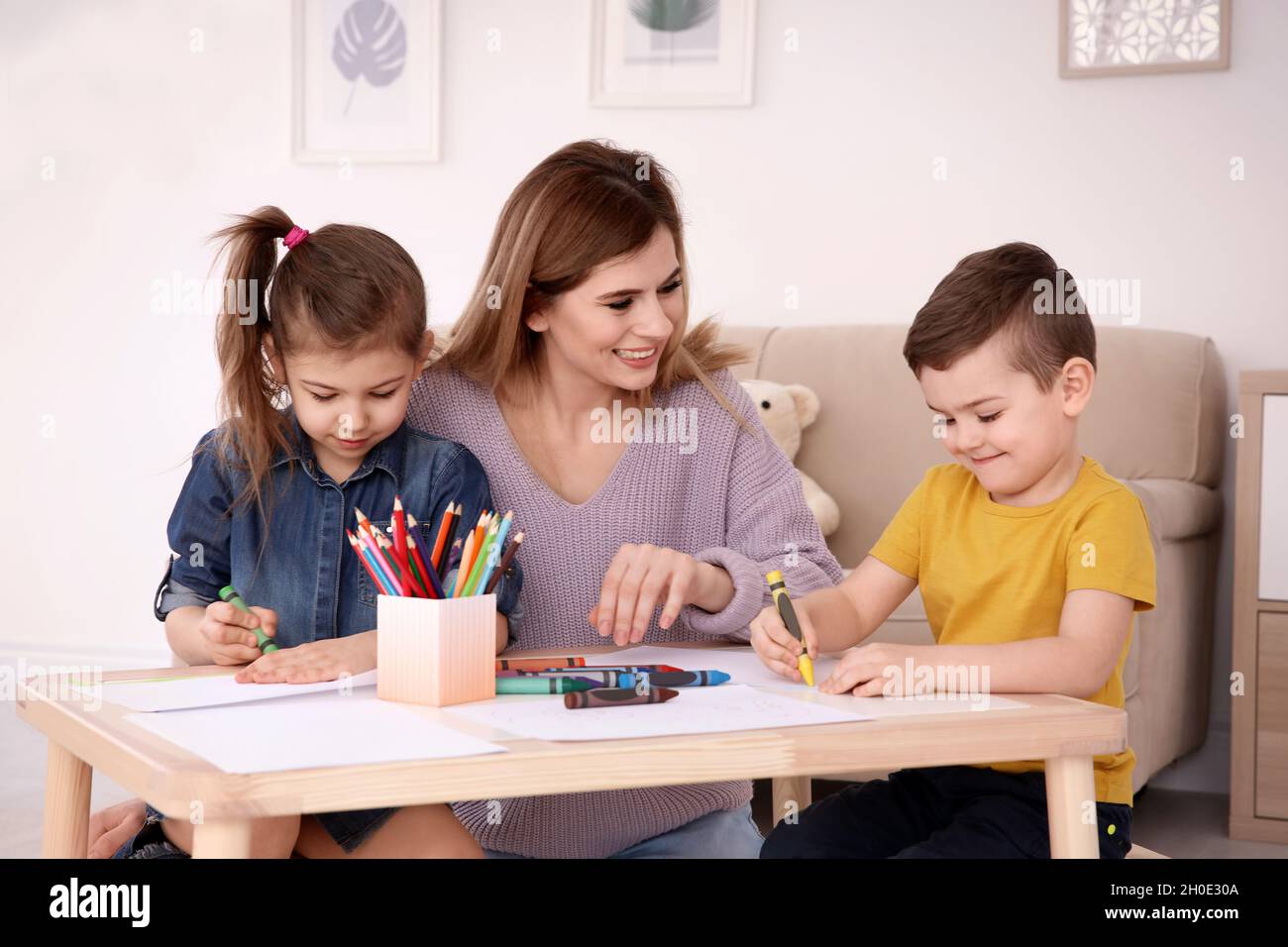 Cute little children and their nanny drawing at home Stock Photo - Alamy