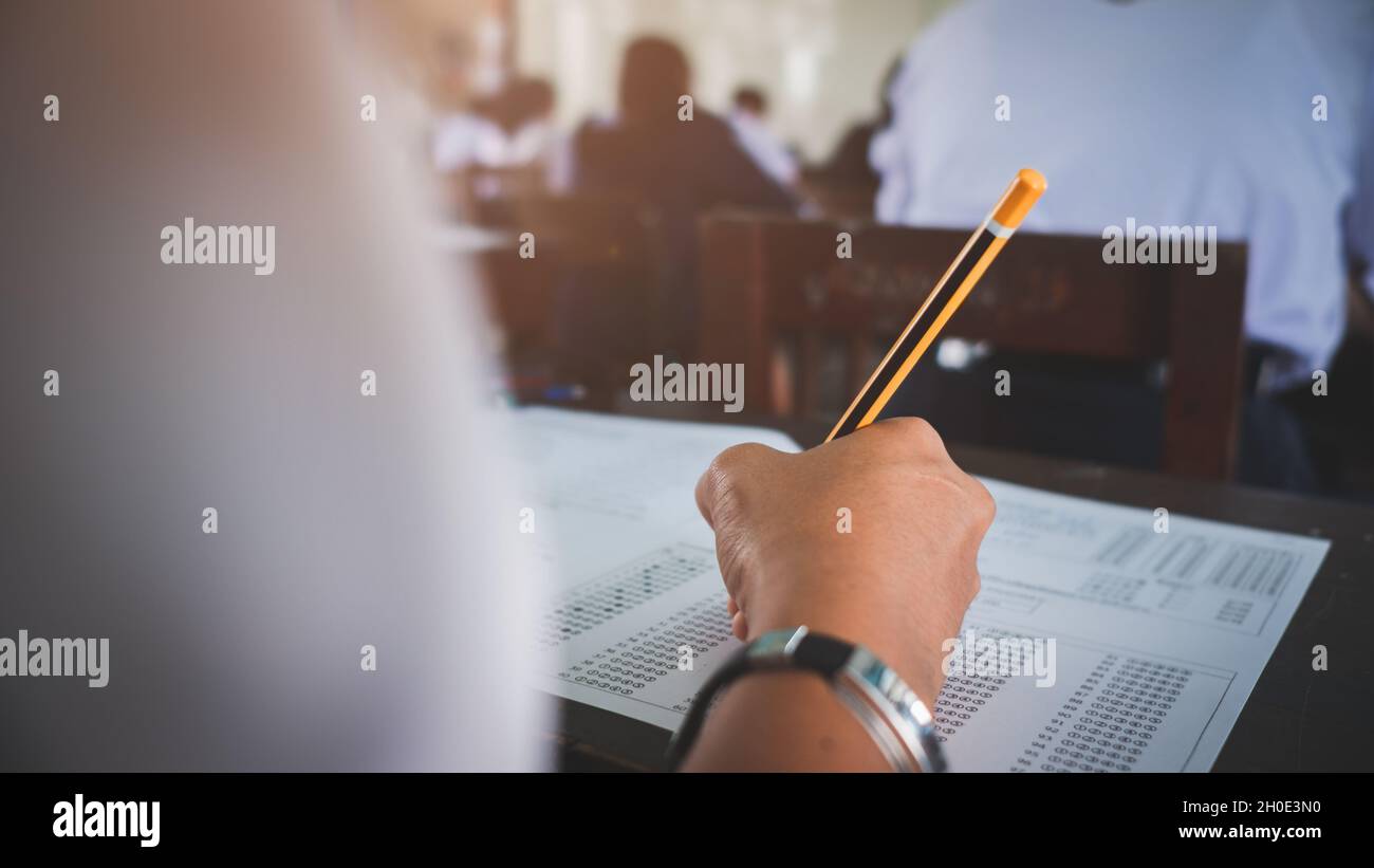 Students writing and reading exam answer sheets exercises in classroom ...