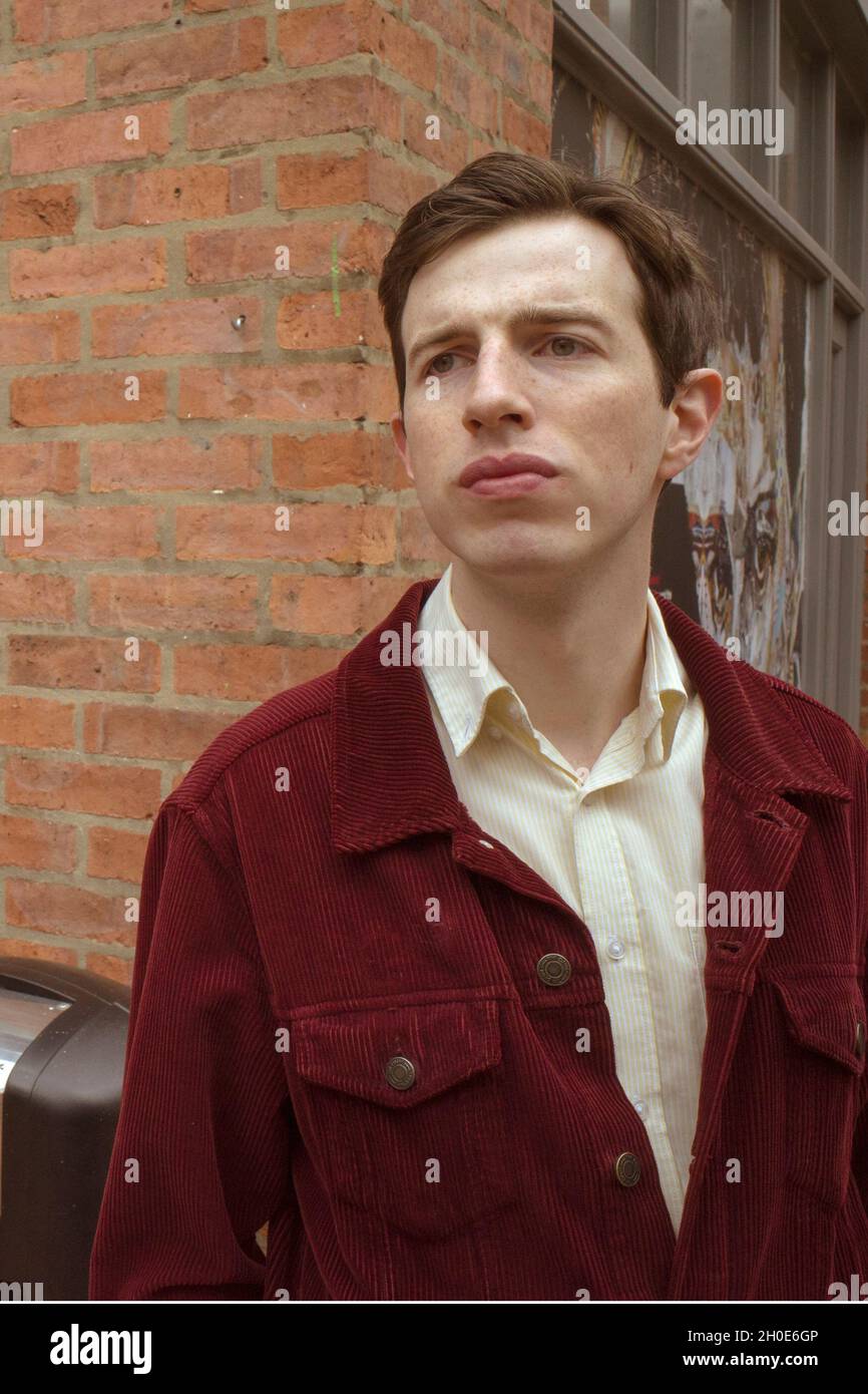 A good looking young man stands in the street outside a building ...