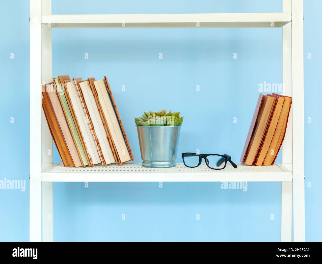 White metal rack with books against blue background Stock Photo - Alamy
