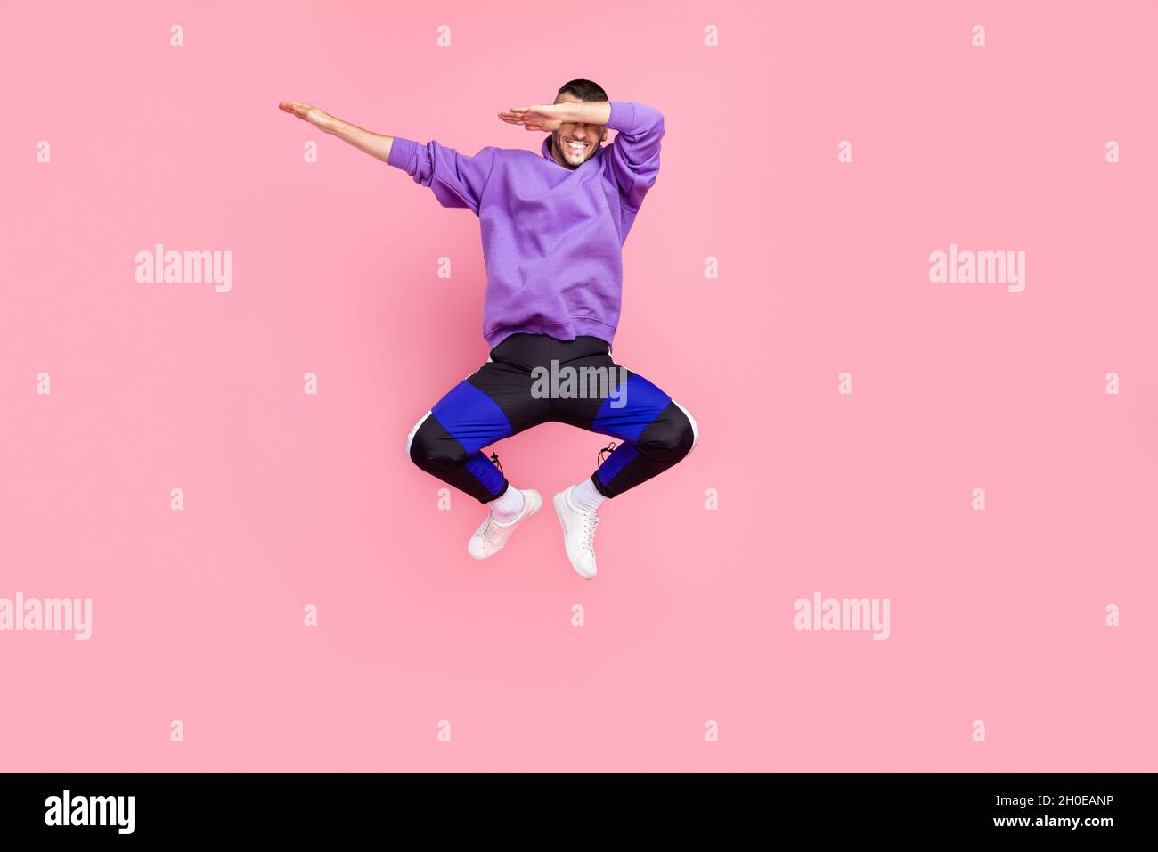 Full body photo of young excited man dance dab cover eyes hands jump up ...