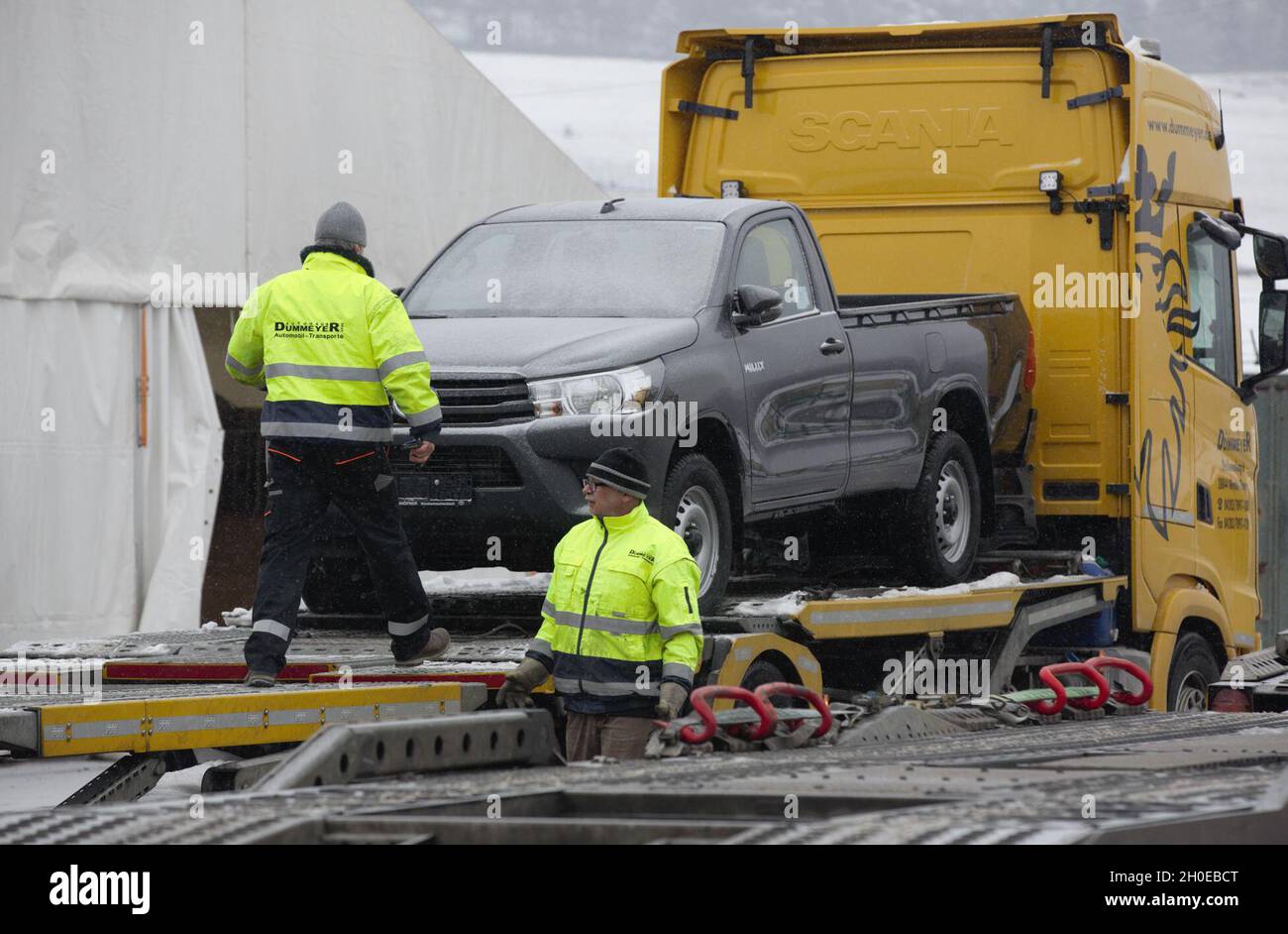 Autohaus Dummeyer employees unload a vehicle from a car carrier trailer ...