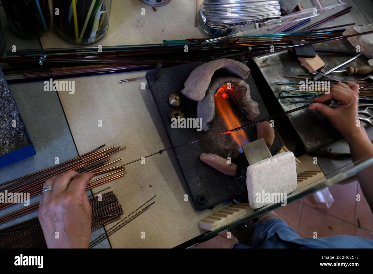 A flame worker's hands during the making of glass beads.this art was ...