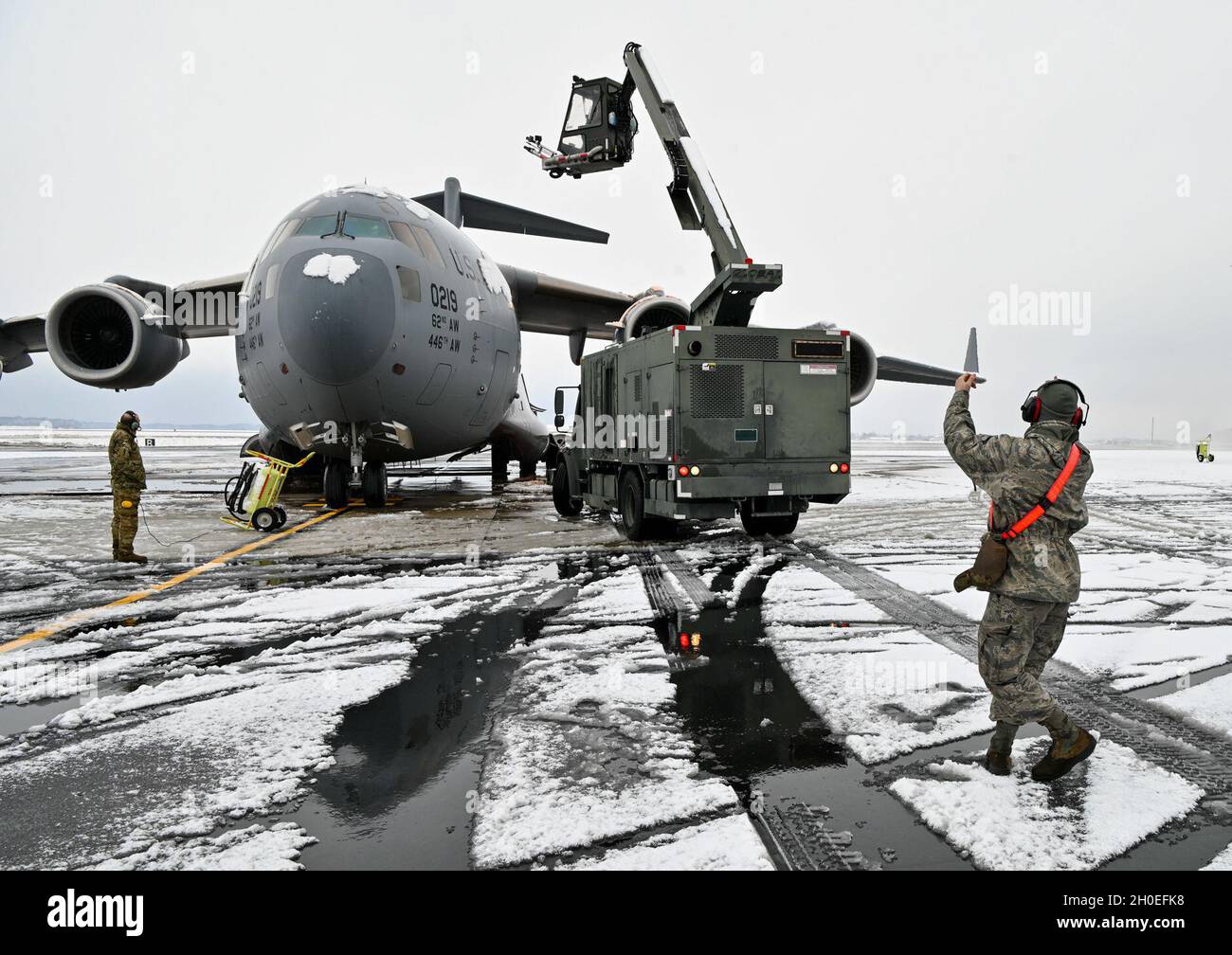 An aircraft de-icing team marshals a de-icing vehicle at Dover Air Force Base, Delaware, Feb. 11 ...