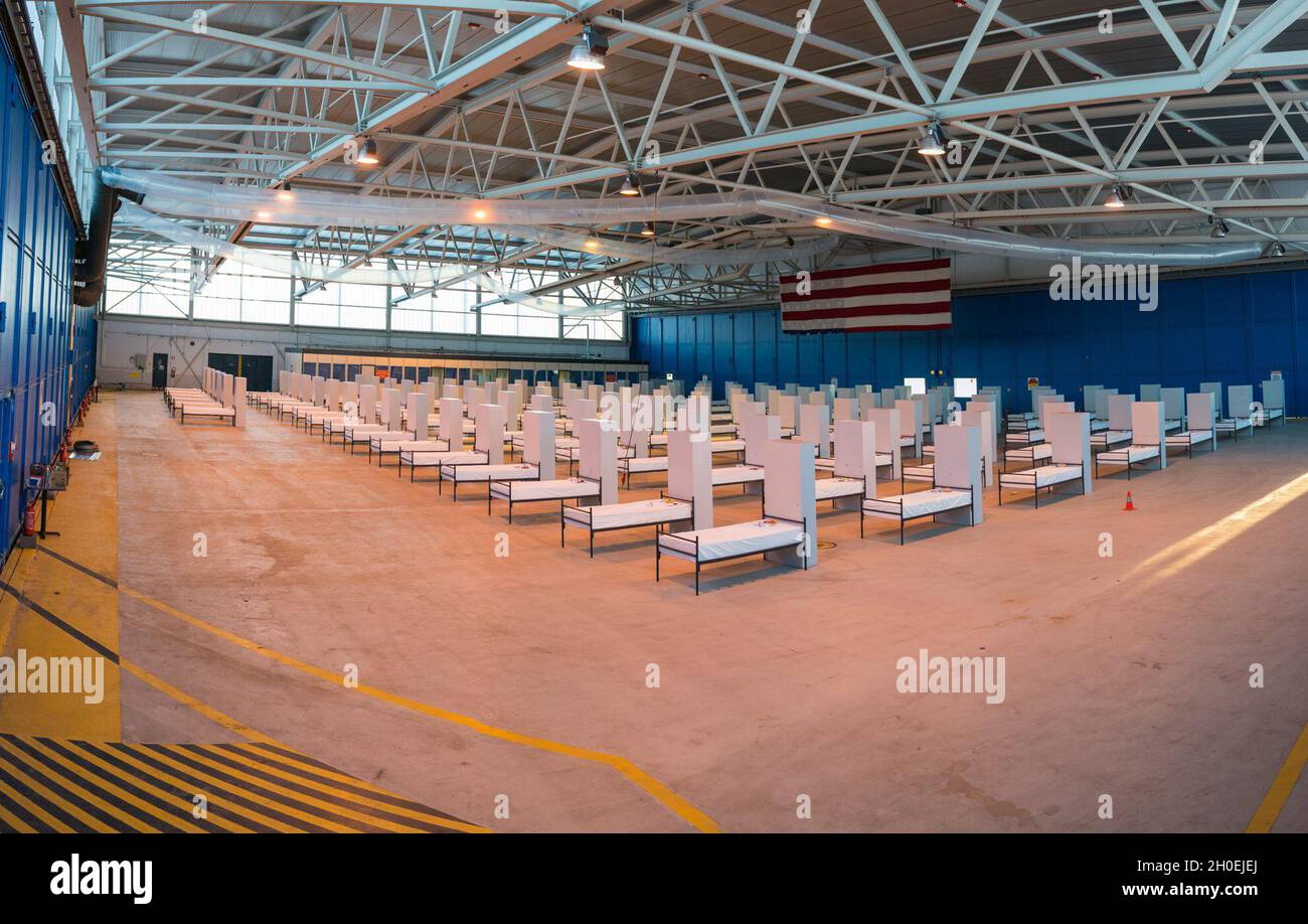 Hundreds of beds lay under heating and ventilation ducts inside hangars ...