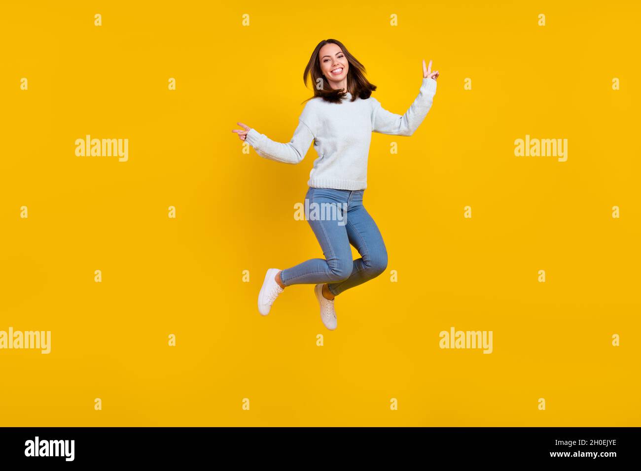 Full size photo of cheerful positive cool young woman jump up make v ...