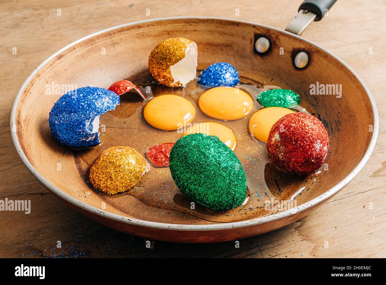Egg yolks and egg shells covered in colorful glitter in cooking pan ...