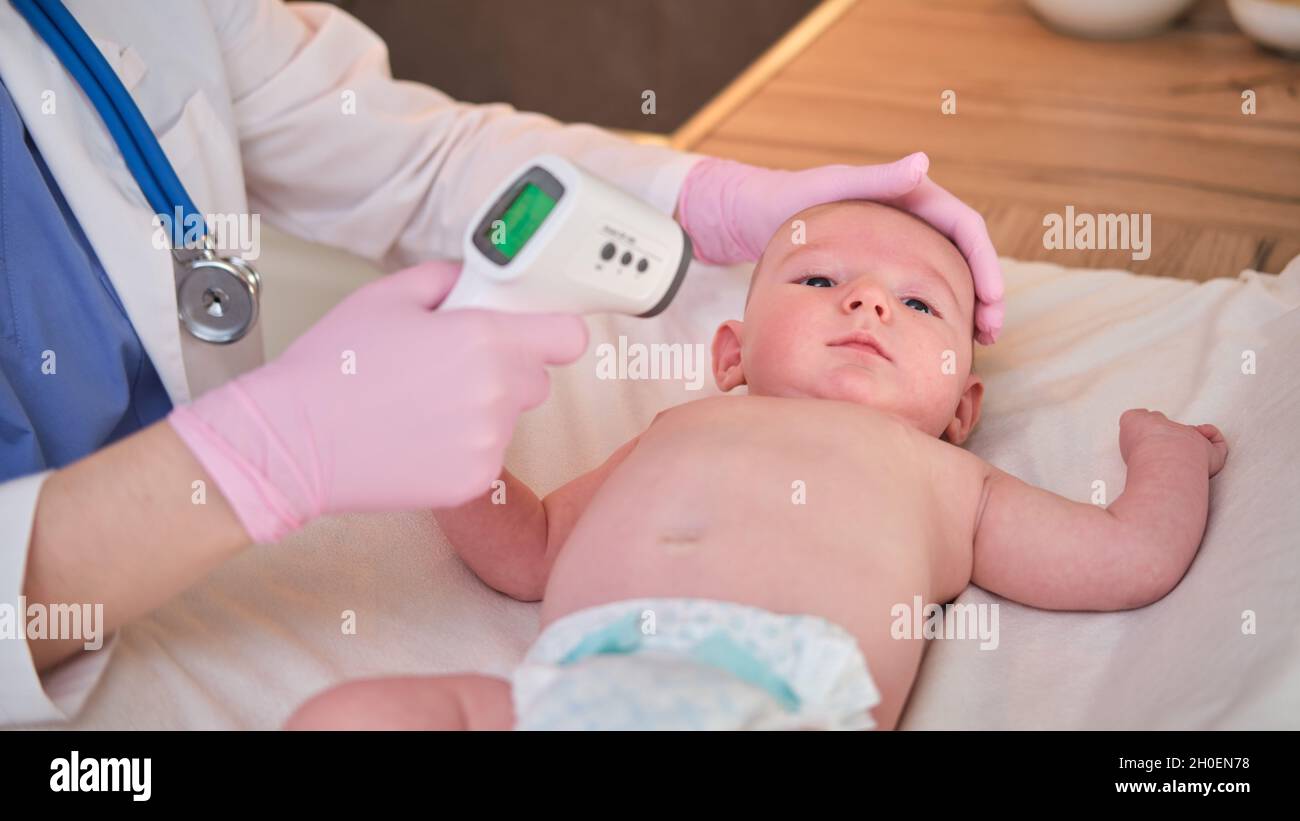 Doctor checks the temperature of the newborn baby with a thermometer. A ...