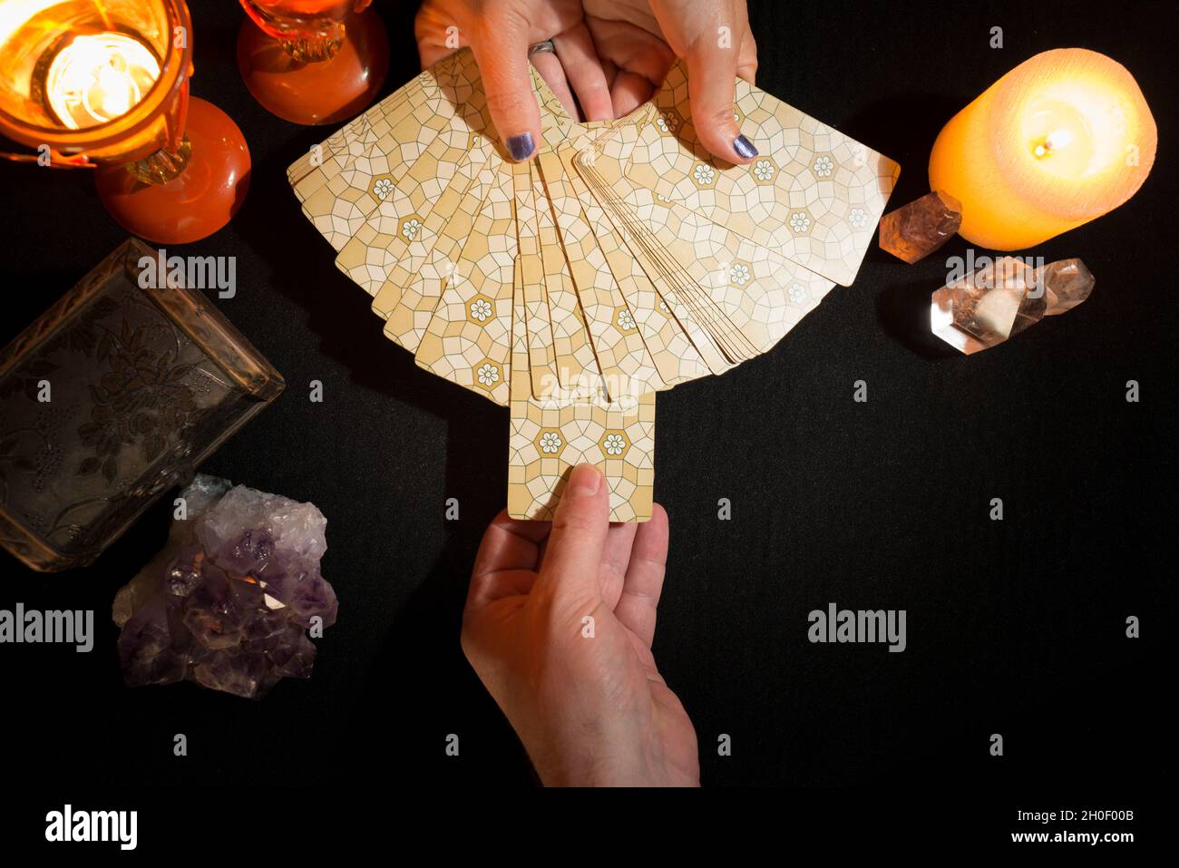 Detail of a woman's hands showing tarot cards while another hand takes ...