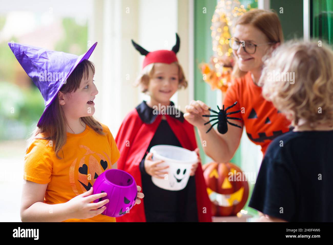 Kids trick or treat on Halloween night. Child at decorated house door ...
