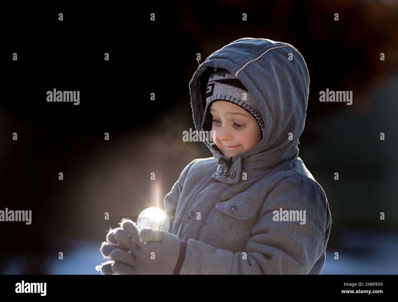 Little boy in jacket with gloves holding lightning ball and having ...