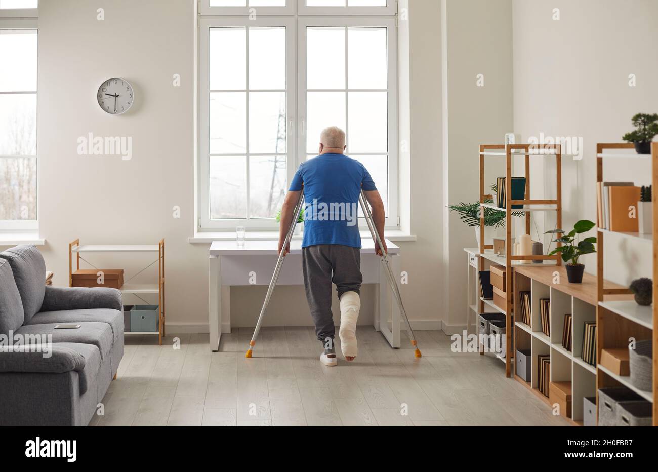Senior man with broken leg in plaster cast using crutches and walking ...