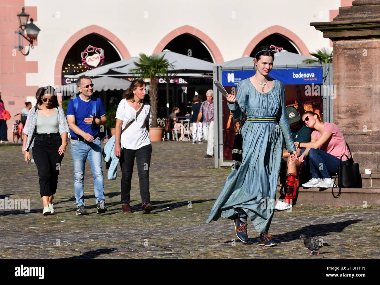 Elegant tour guide carrying lamp on cobbled street in Freiburg Germany ...