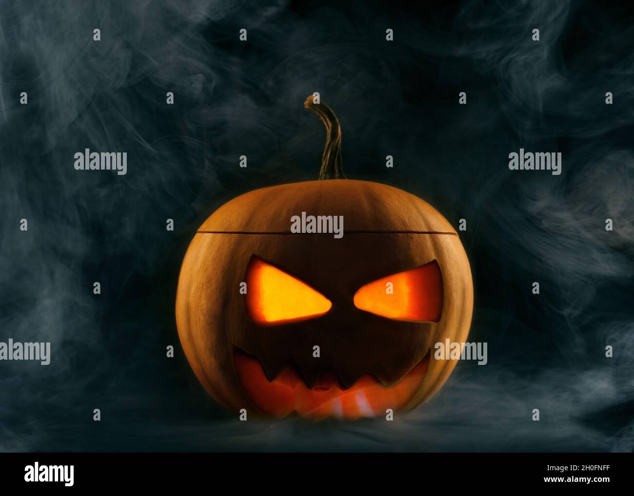Spooky carved pumpkin for Halloween celebration with smoke and fog ...