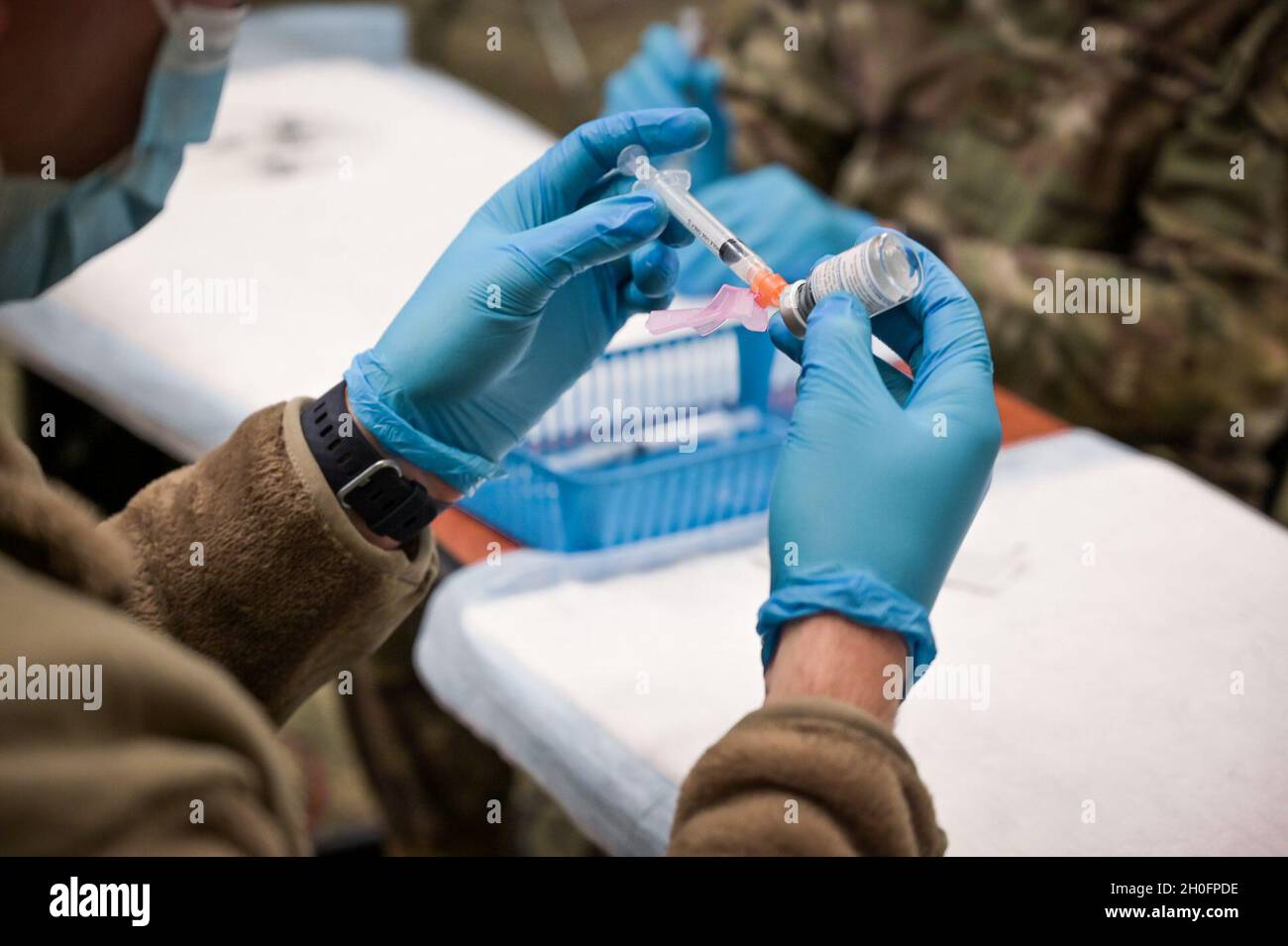 U.S. Army combat medic draws the COVID-19 vaccine into a syringe in the ...