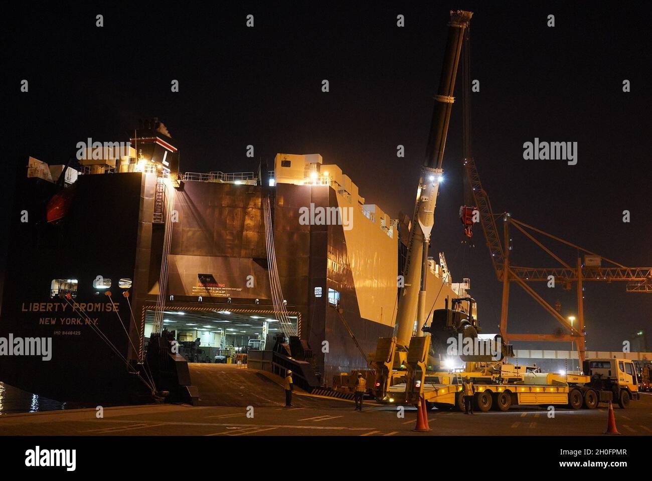 A roller compactor is hoisted by a crane from the Liberty Promise onto ...