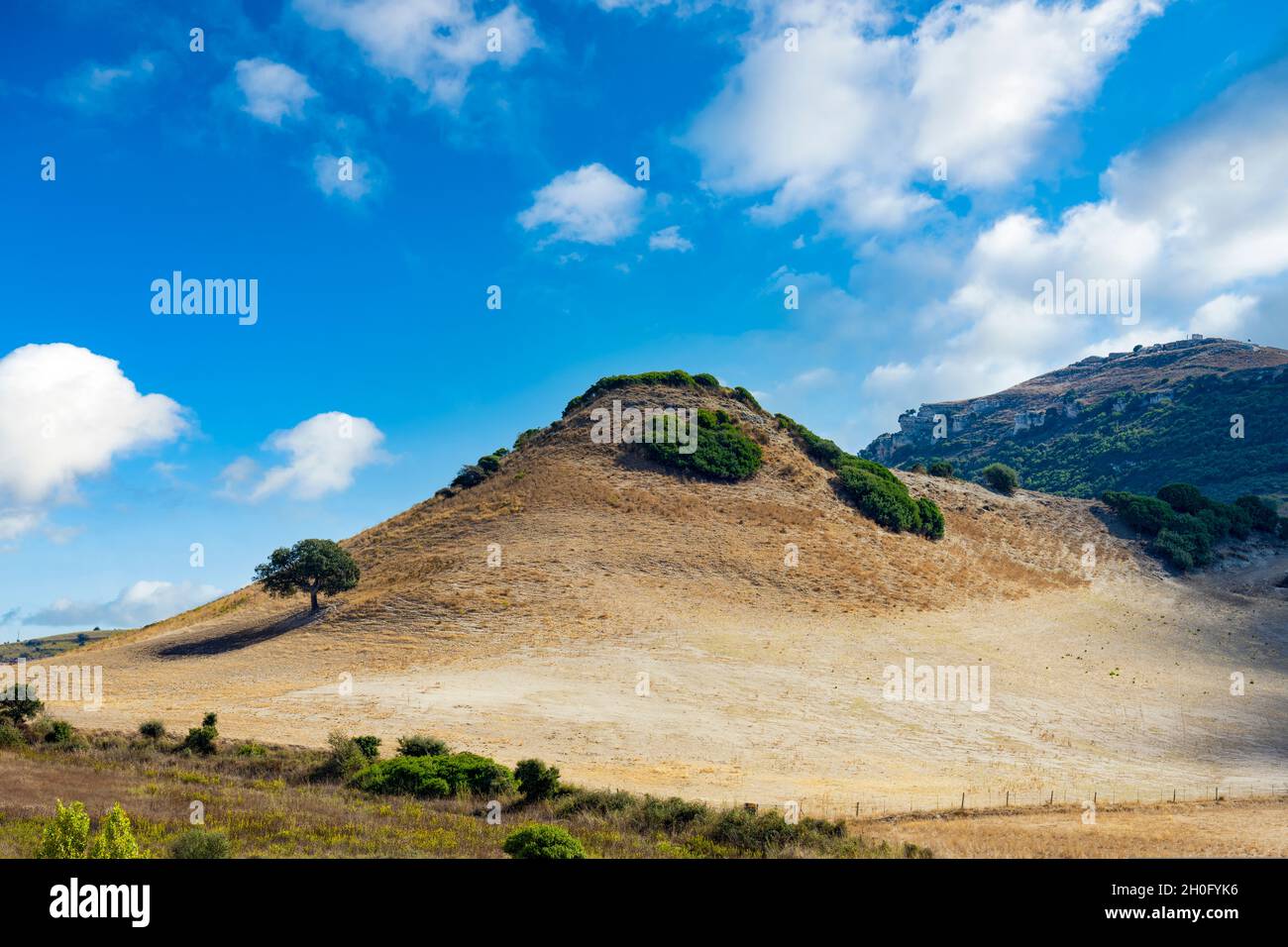 Stunning view of a pyramid shaped hill with a blue, cloudy sky ...