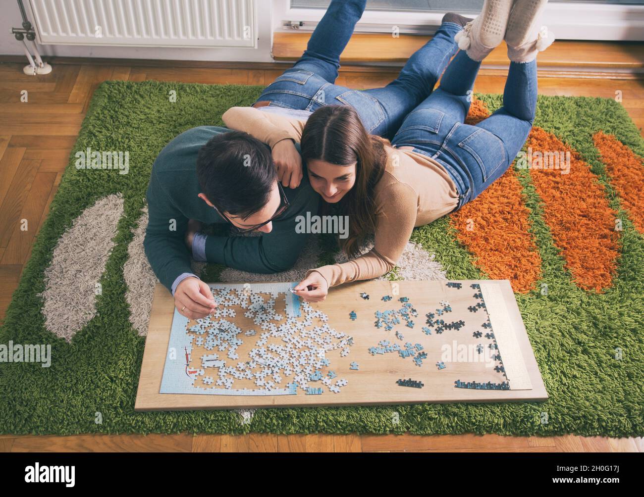 Top view of young couple laying on floor and doing puzzle Stock Photo ...